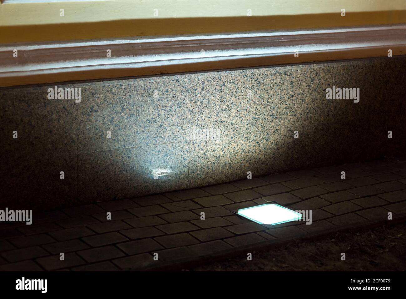 Built in ground lantern in stone tile illuminate granite facade of ...