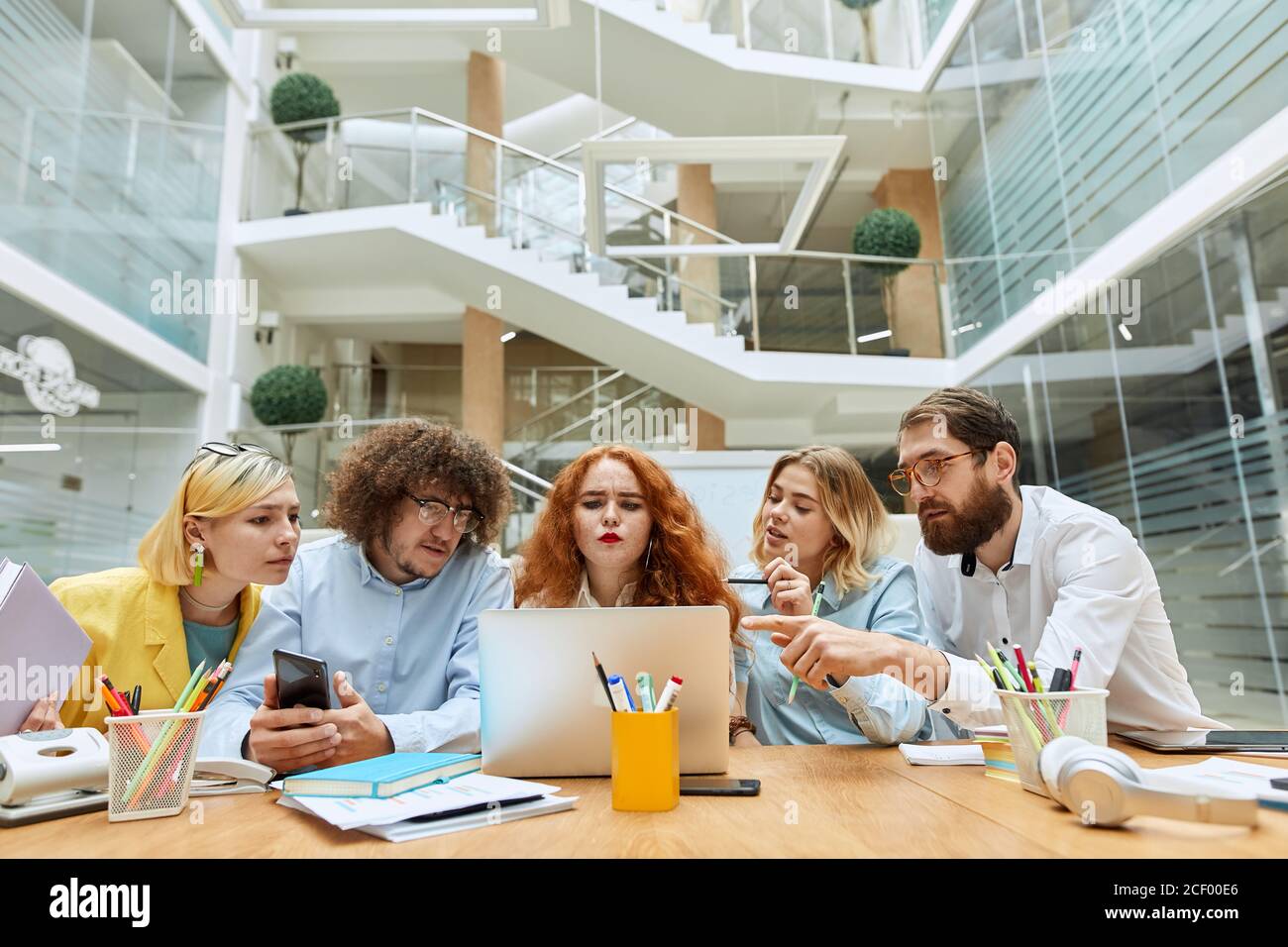 Excited stressed colleagues sit at working table, stare at laptop ...