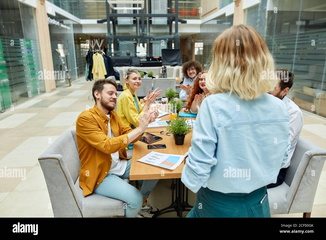 Positive bright colleagues cheerfully applaud young good shaped woman ...