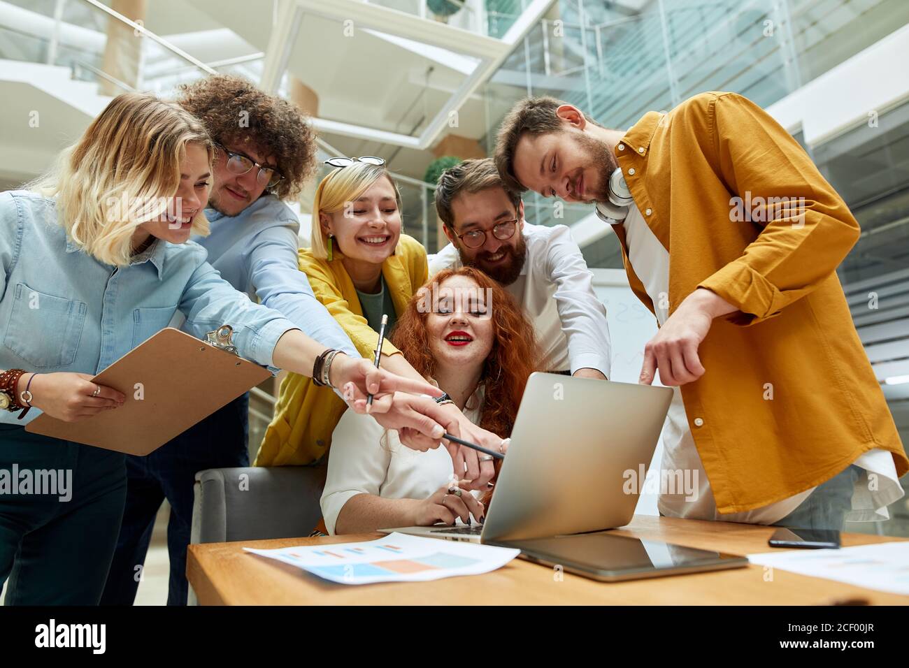 Optimistic playful young designers happily spend time at work, stand in ...