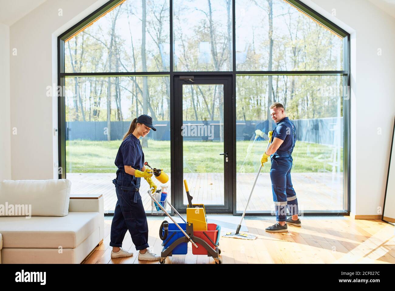 Two janitors clean country house with panoramic window, wash floors ...