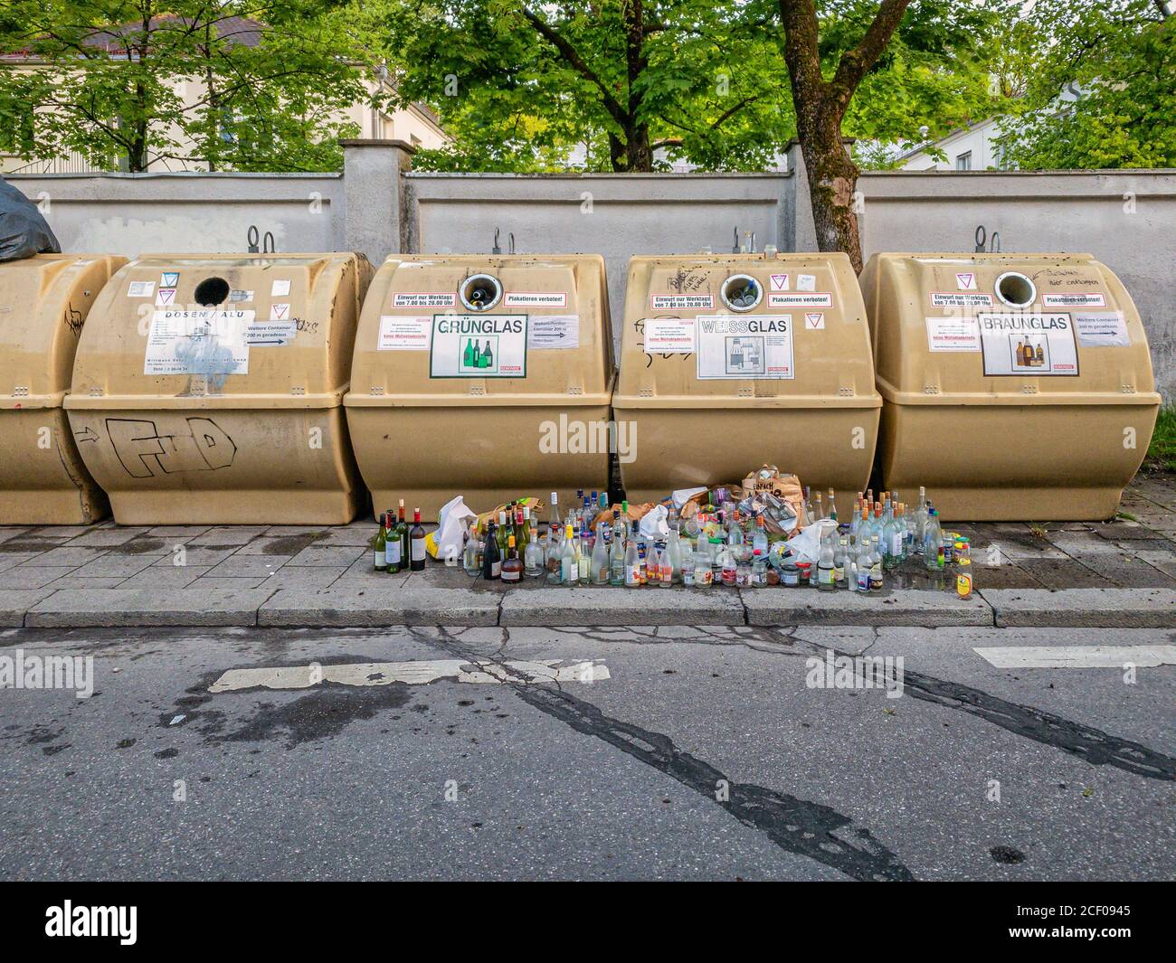 Empty bottles standing in front of overfilled containers in a city. A ...
