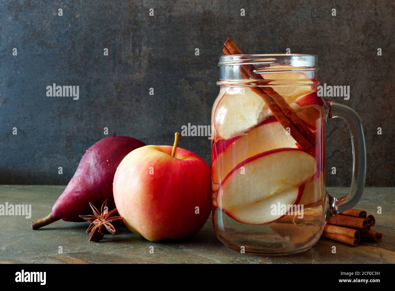 Autumn themed detox water with apple, cinnamon and red pear in a mason ...