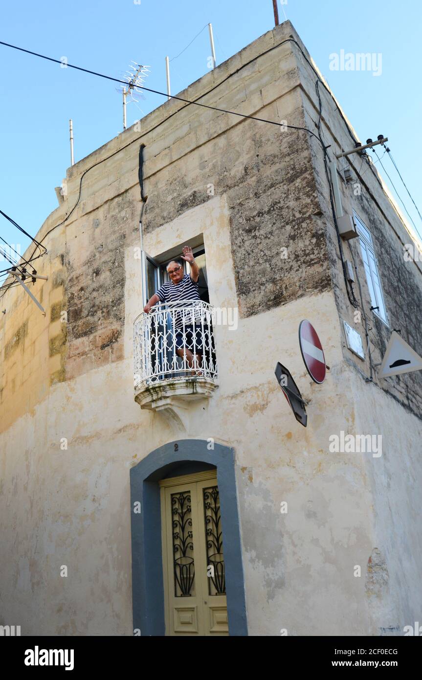 A Maltese man looking down on the street from his balcony Stock Photo ...