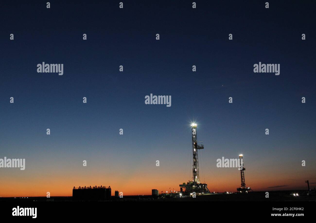 View of west texas desert landscape at dawn with two drilling rigs in ...