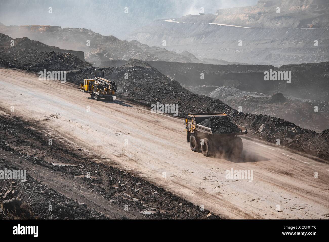 Drilling car and big yellow mining empty truck with dust transportation ...