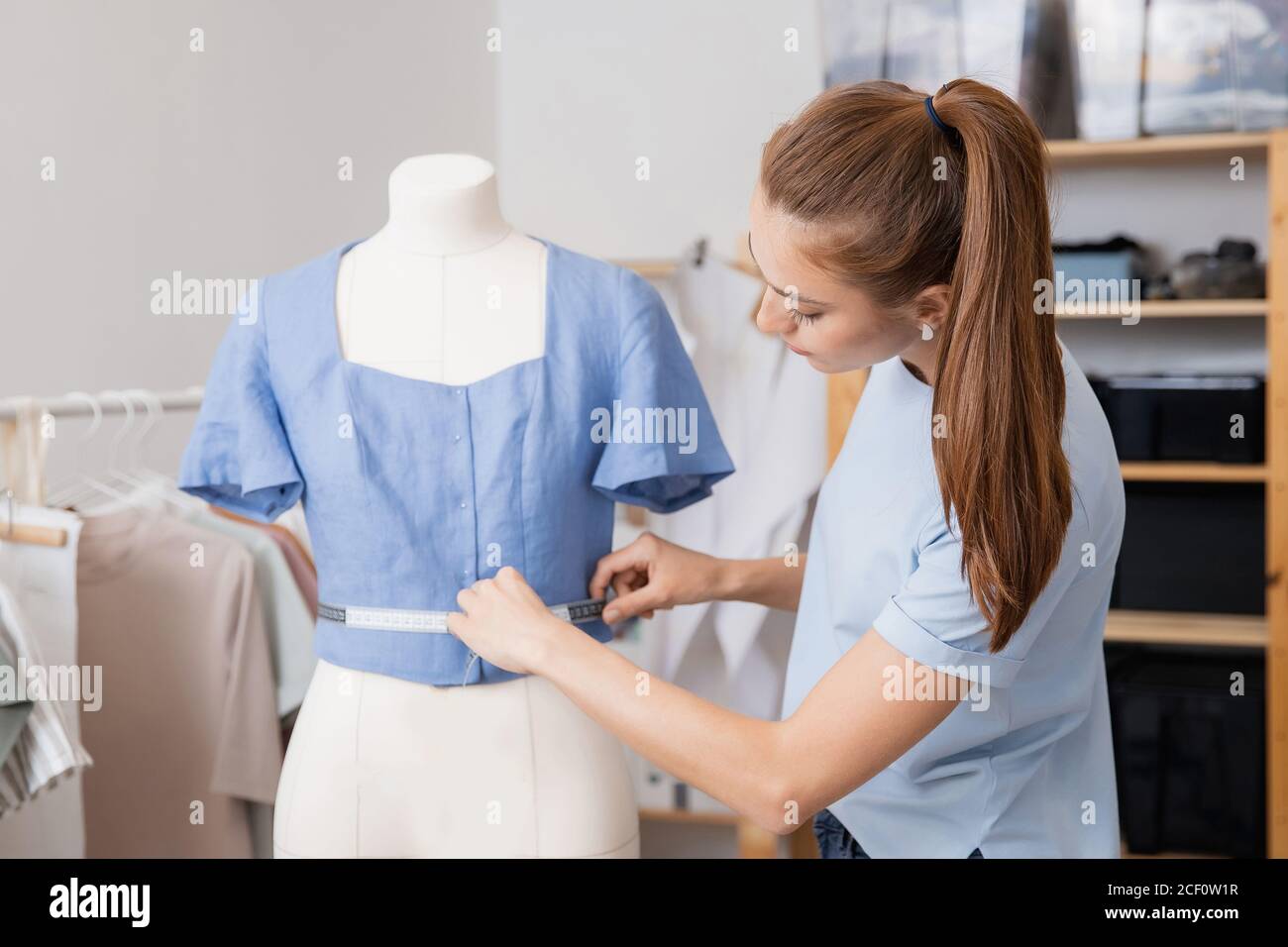 Seamstress woman takes measurements from mannequin with measuring tape ...