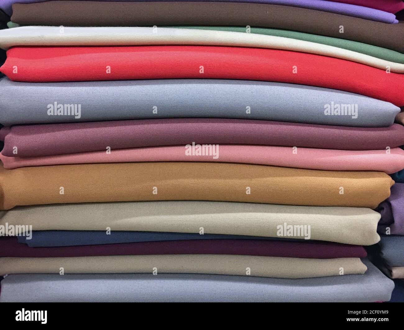 A lot of pastel colored cotton fabric in a shop counter. Asian garment ...