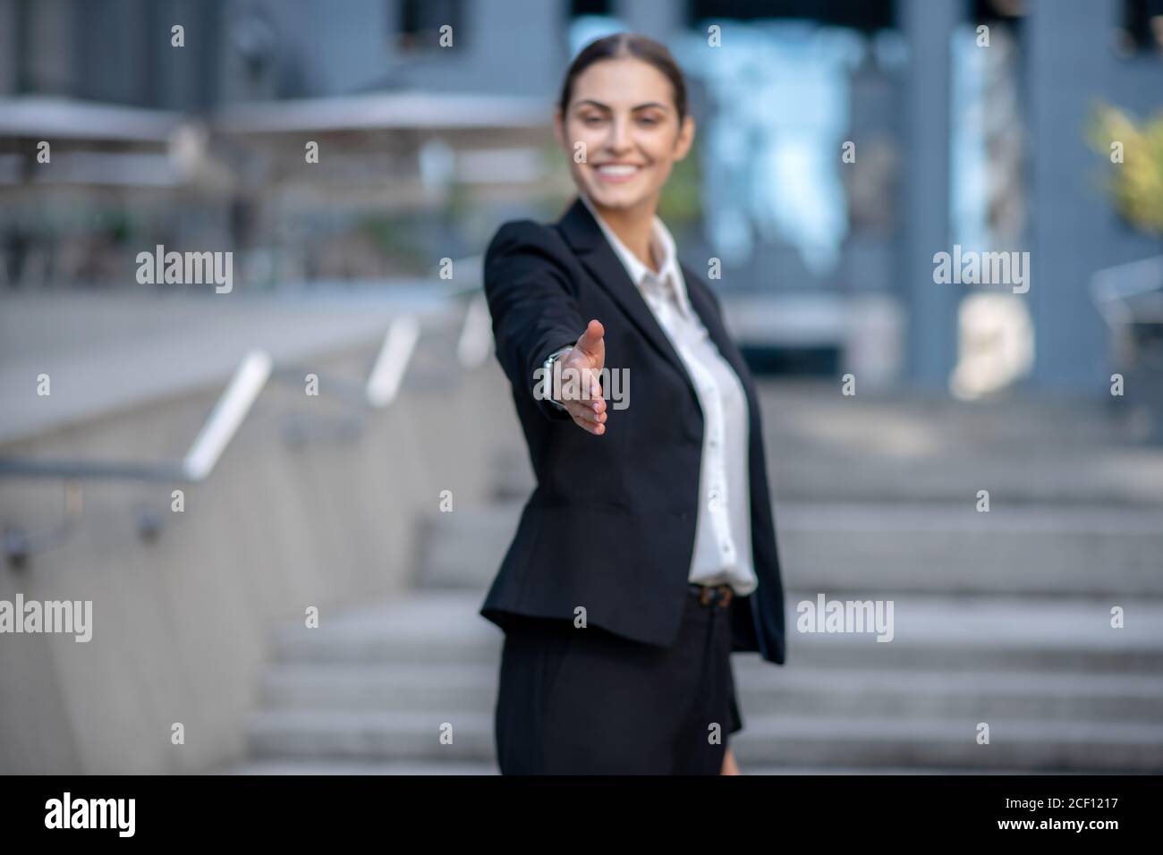 Beautiful woman in a suit stretching her hand in greeting Stock Photo ...
