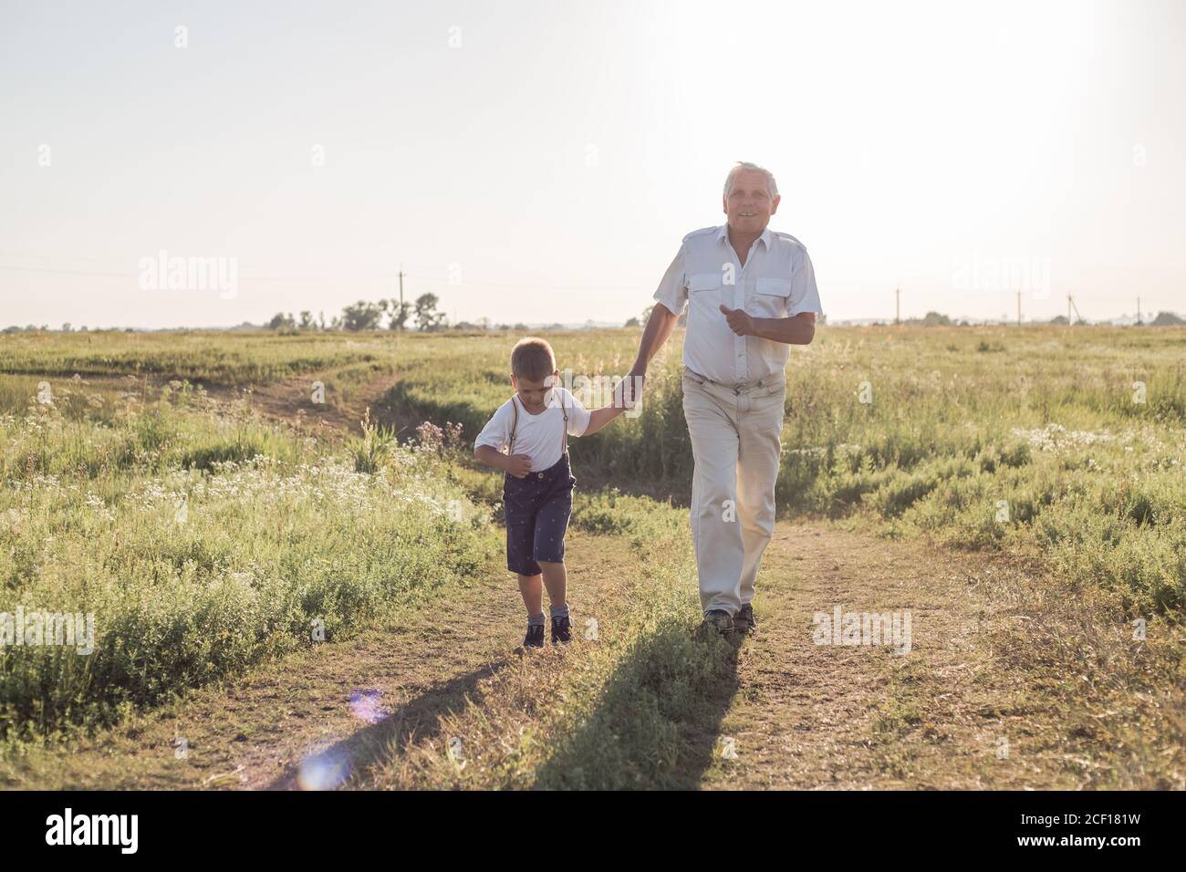 Happy child with Grandfather playing at the meadow. Grandpa retiree ...