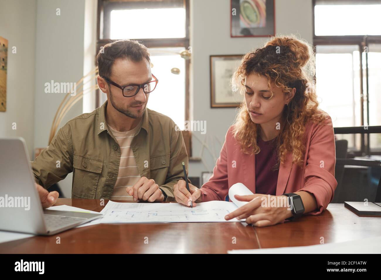 Two designers sitting at the table and working in team they drawing ...