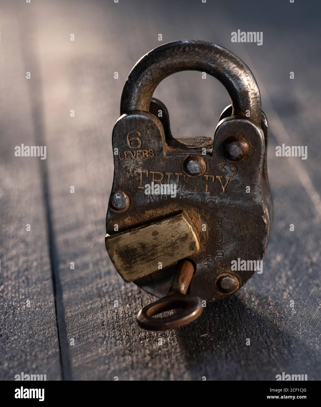 Trusty Padlock with key on weatehered textured wooden table top book ...