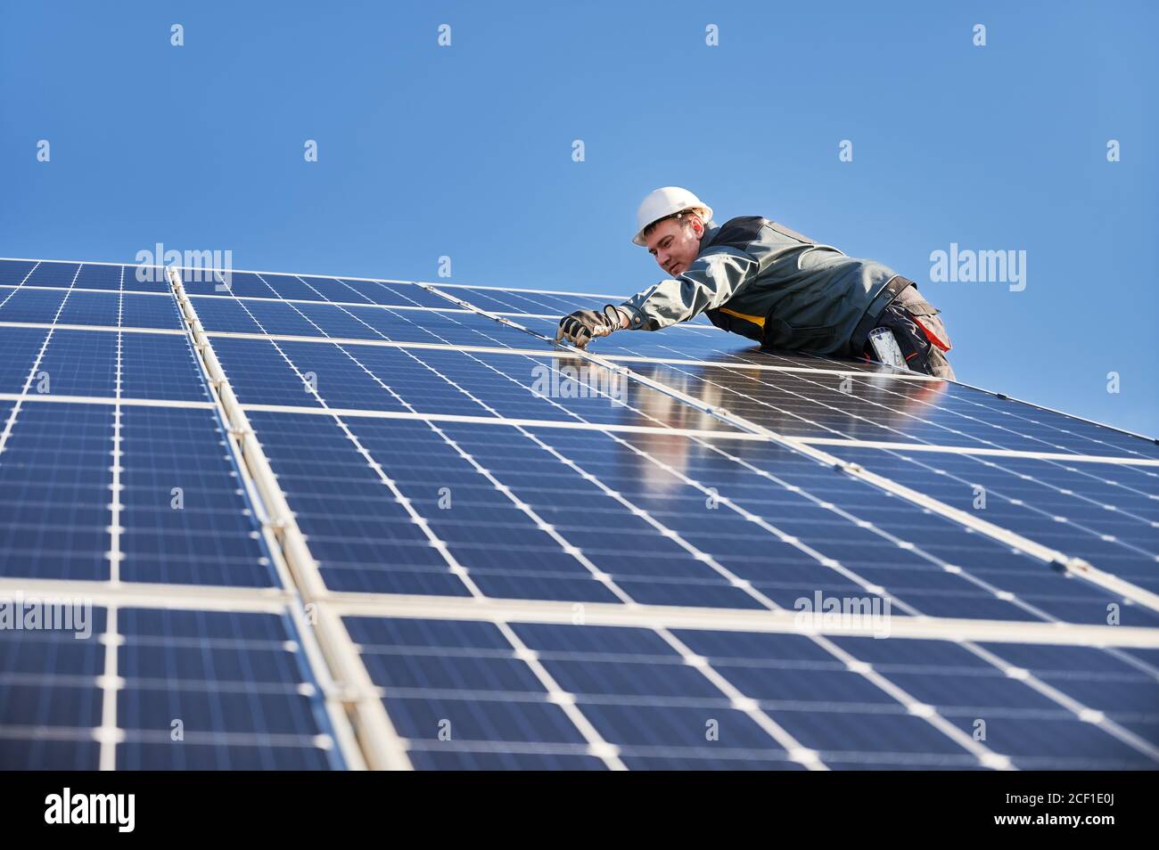 Side view of male worker installing solar modules and support ...