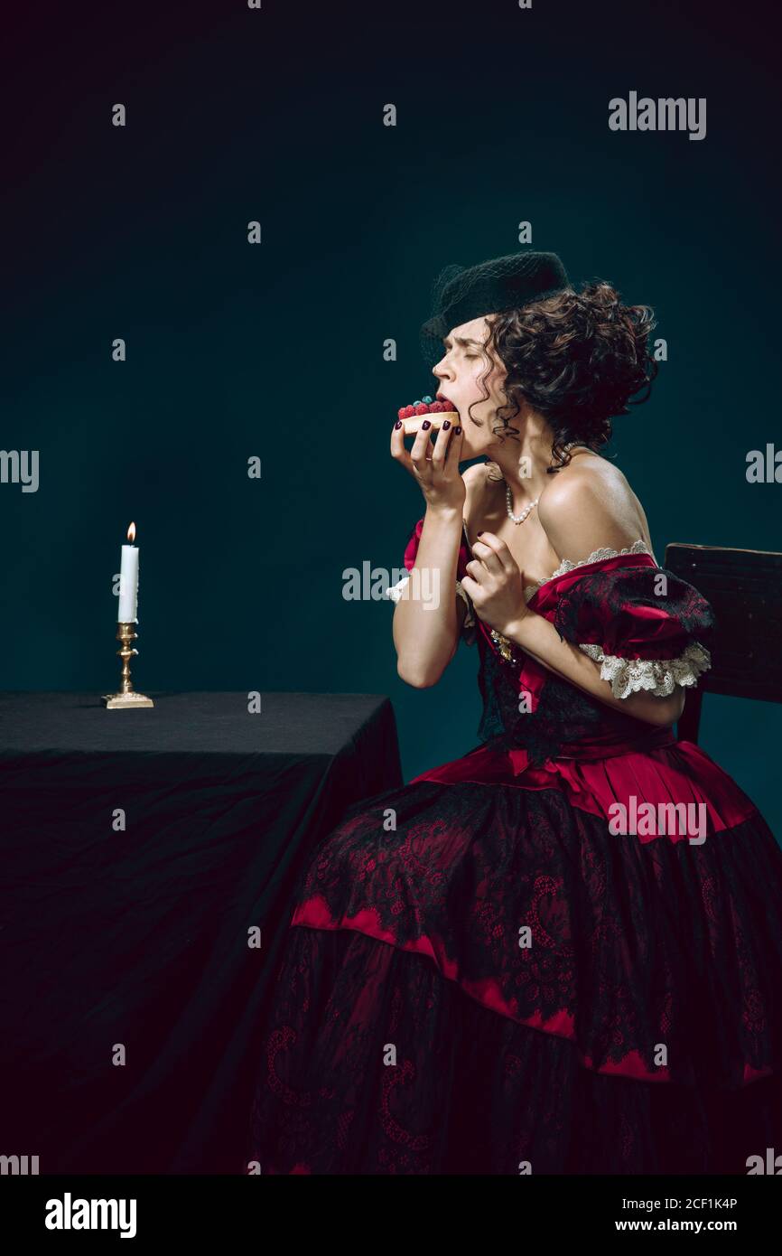 Diet and sweets. Young woman as Anna Karenina isolated on dark blue ...