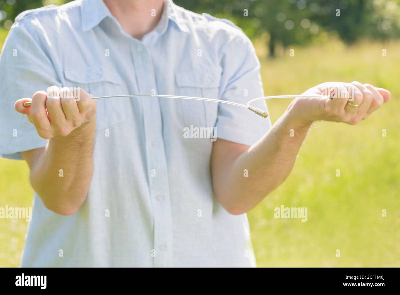 Man dowsing wirh dividing rod to locate ground water under surface or ...
