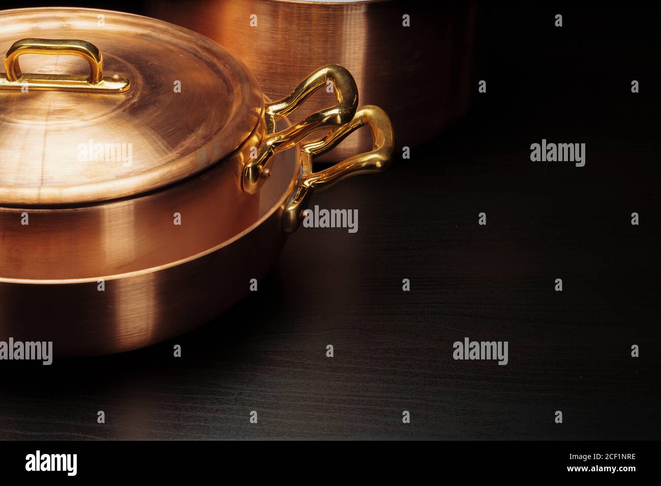 Shiny vintage copper cookware over dark background Stock Photo - Alamy