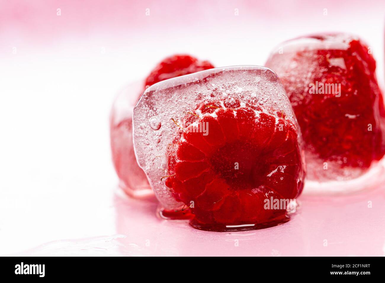 Raspberry ice cubes on pink glossy background Stock Photo - Alamy