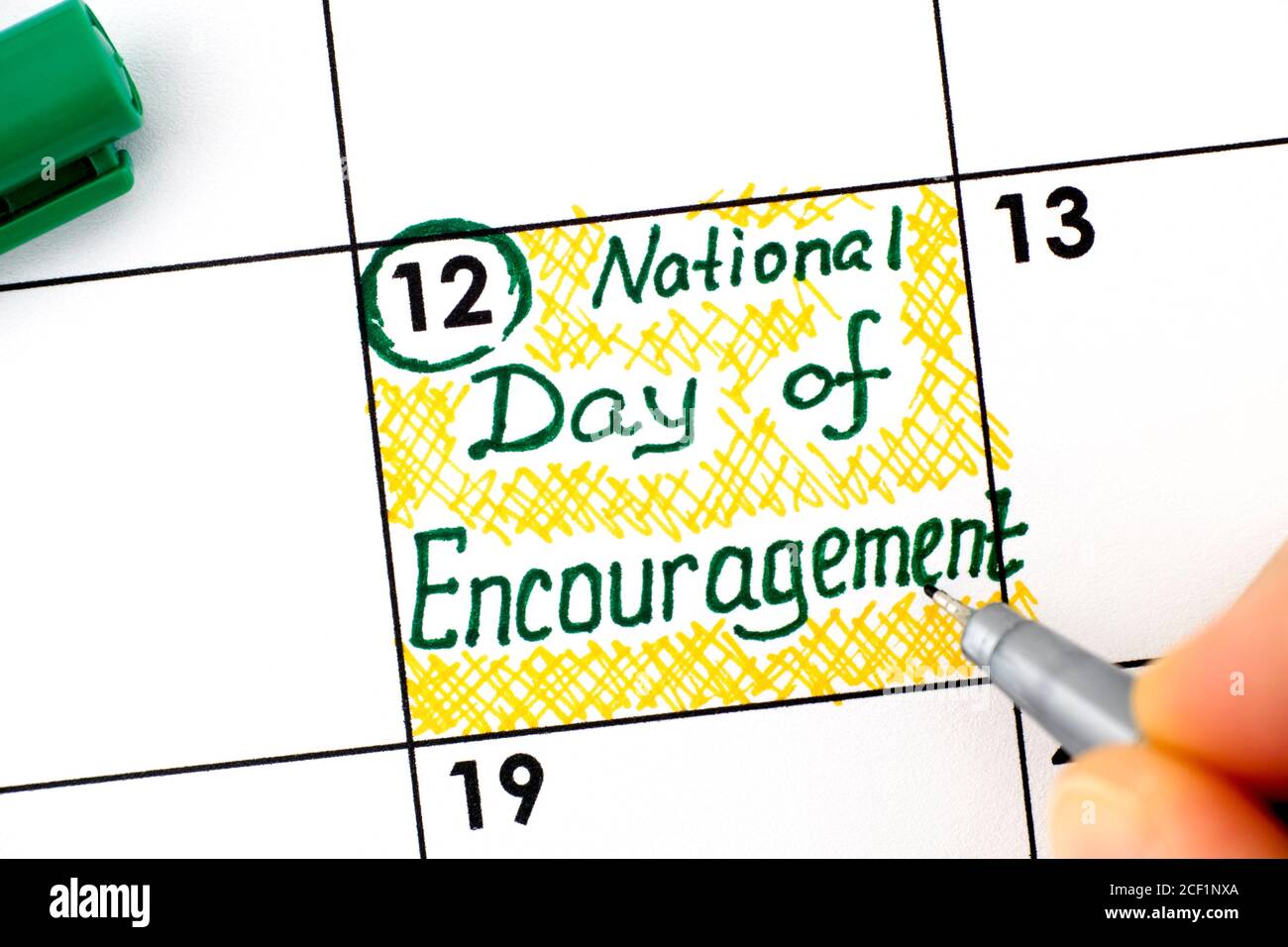 Woman fingers with pen writing reminder National Day of Encouragement ...