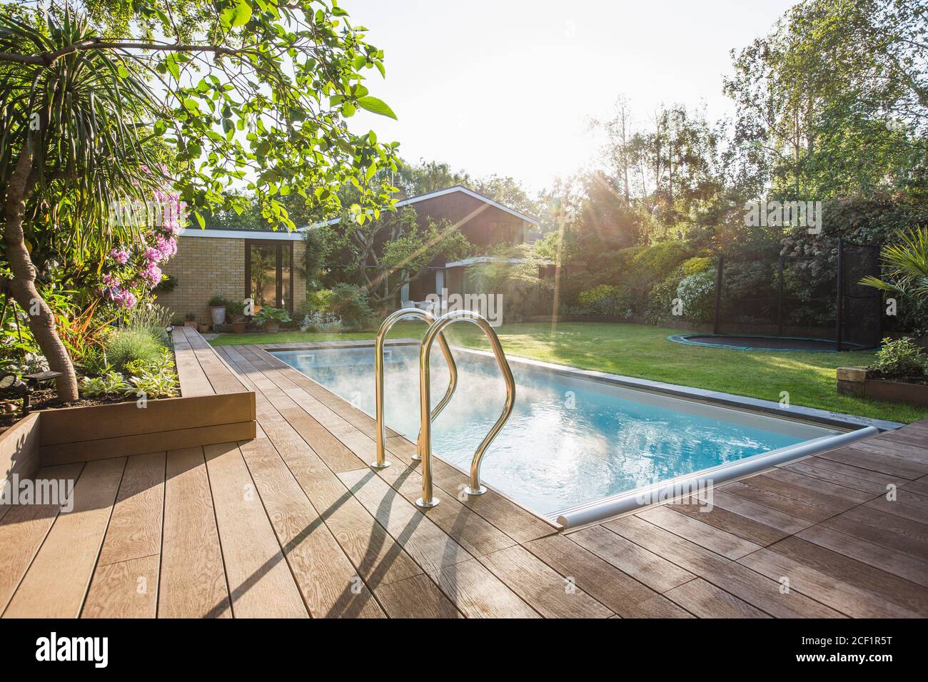 Sunny idyllic home showcase swimming pool and backyard Stock Photo - Alamy