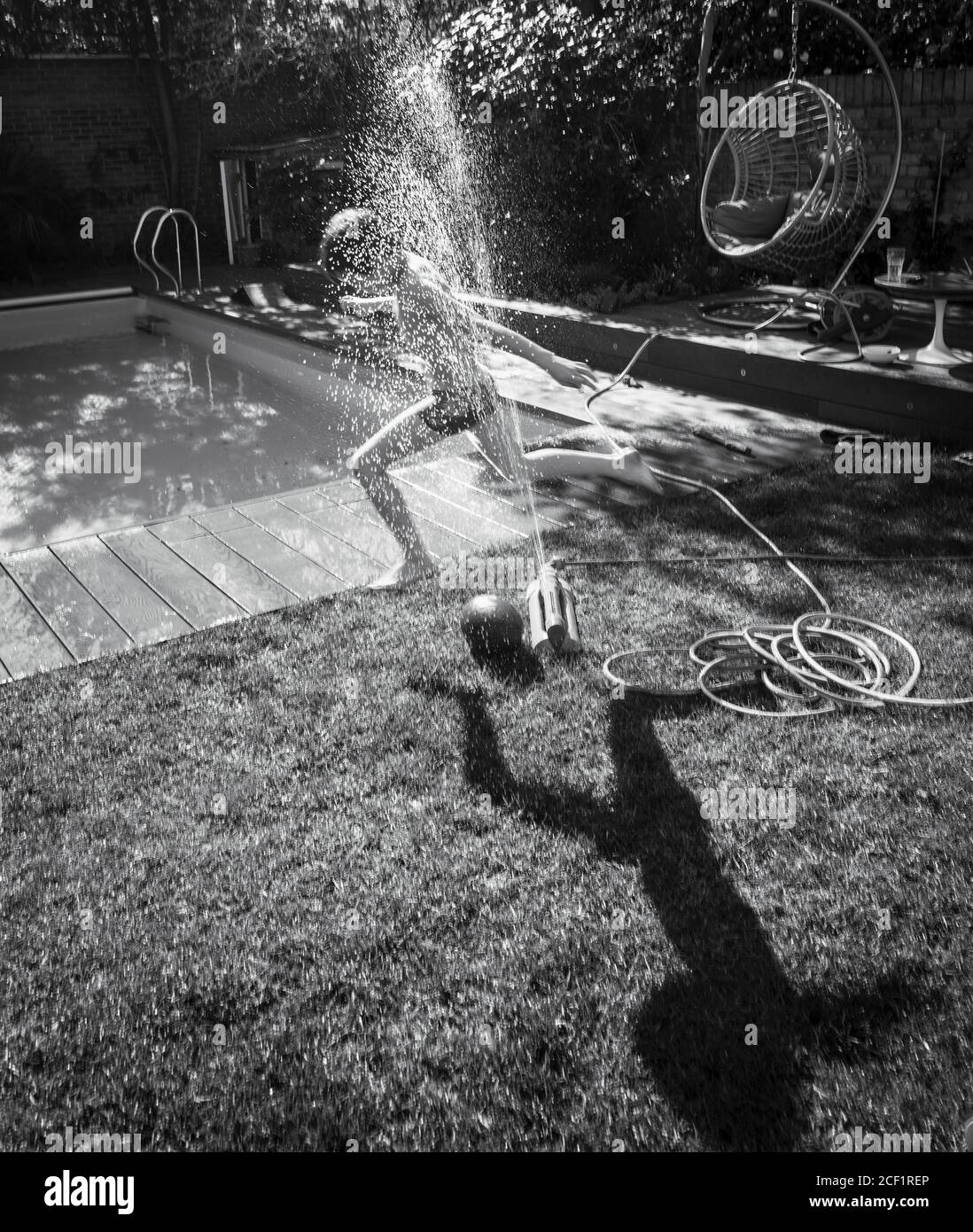 Boy running through sprinkler in sunny summer backyard Stock Photo - Alamy
