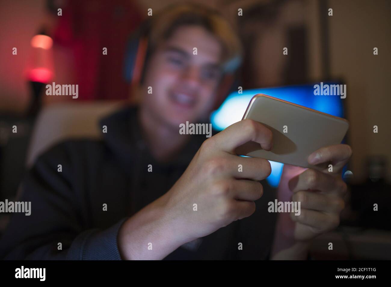 Teenage boy using smart phone in dark bedroom Stock Photo - Alamy