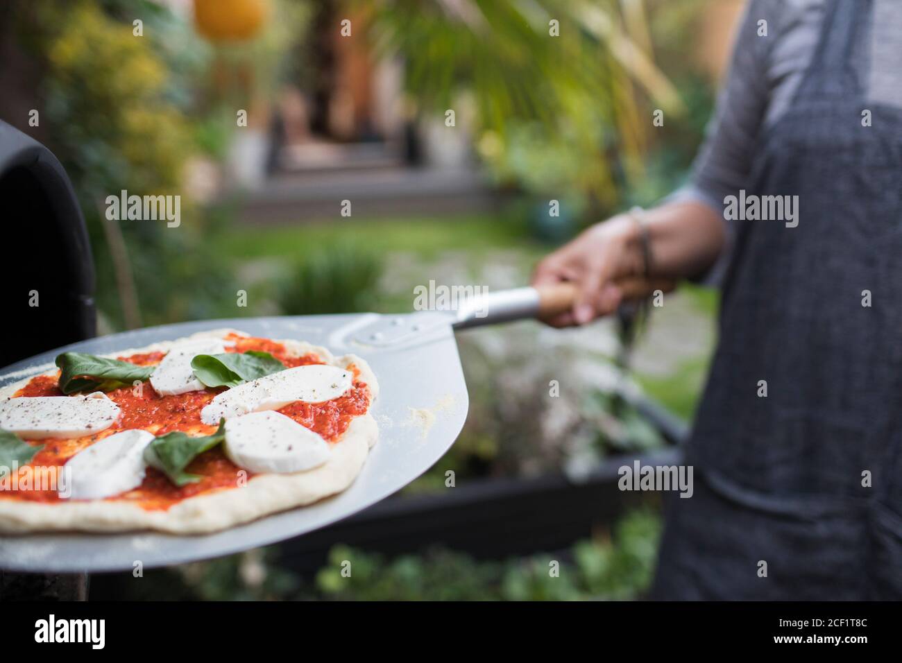 Woman cooking homemade pizza at pizza oven on patio Stock Photo - Alamy
