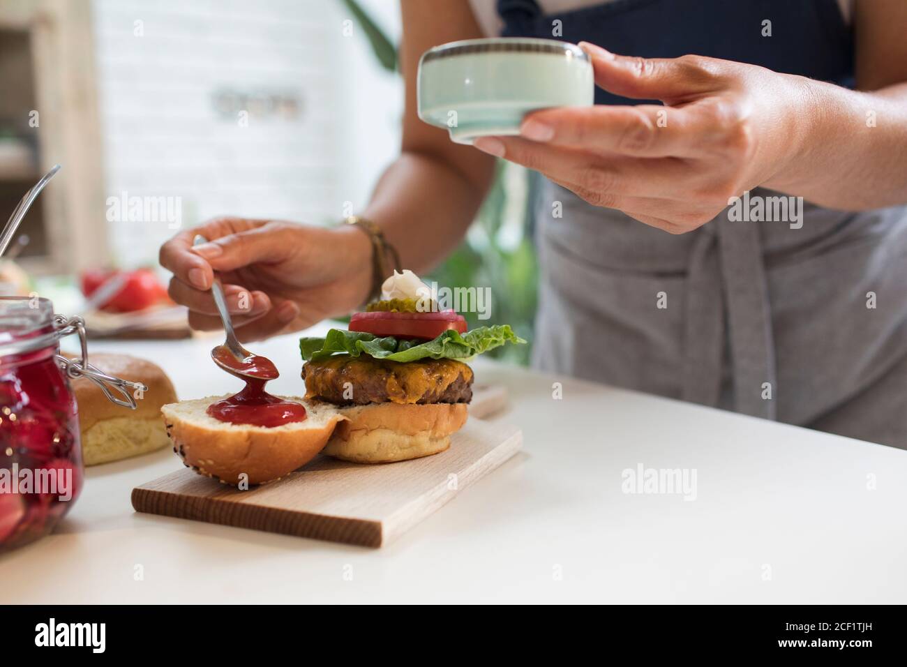 Close up woman spreading ketchup on cheeseburger bun Stock Photo - Alamy