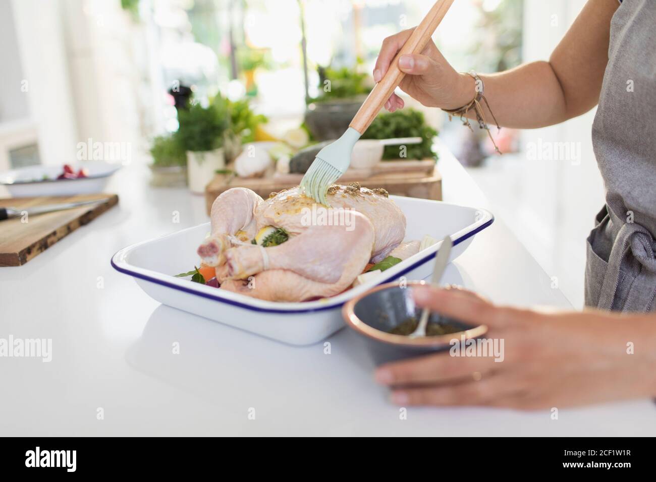 Woman brushing raw chicken with sauce in kitchen Stock Photo - Alamy