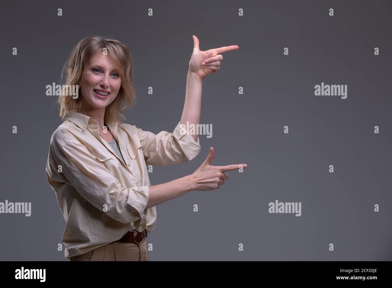 Portrait of a happy smiling woman pointing finger away at copyspace ...