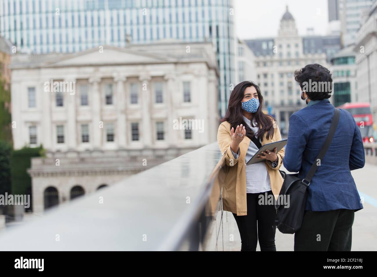Business people in face masks talking on city bridge, London, UK Stock ...