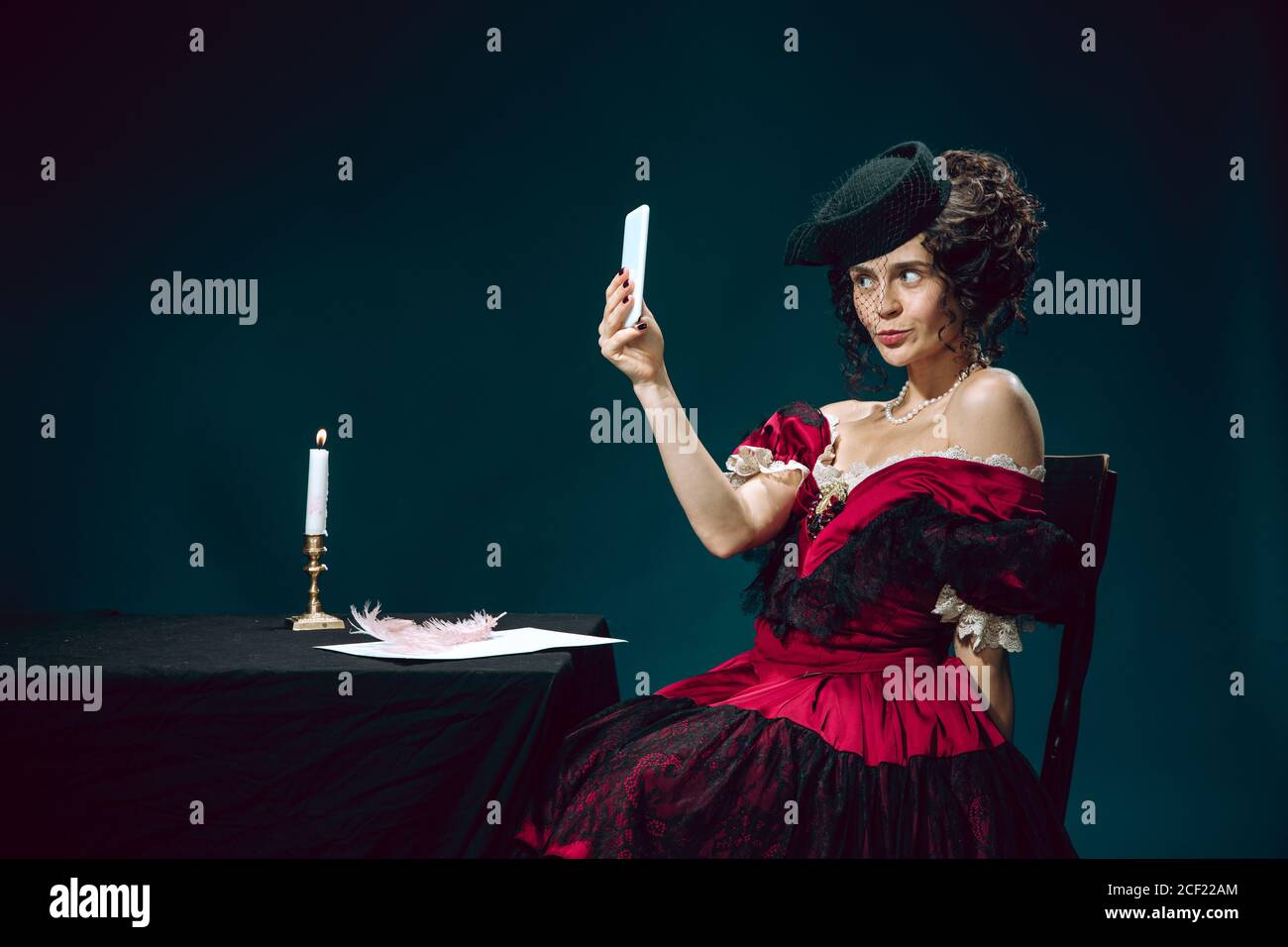Selfie mood. Young woman as Anna Karenina isolated on dark blue ...