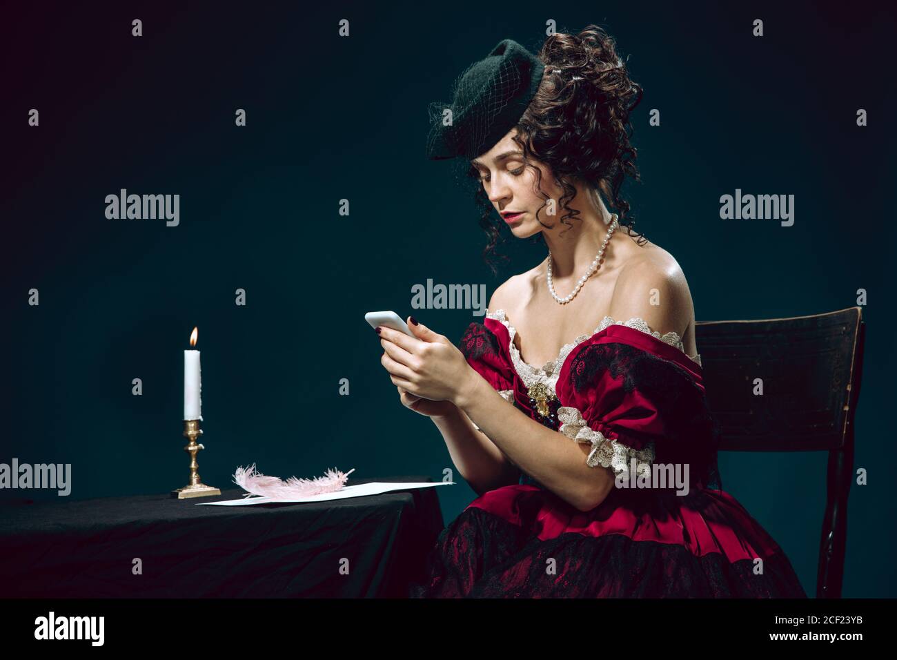 Secret chat. Young woman as Anna Karenina isolated on dark blue ...