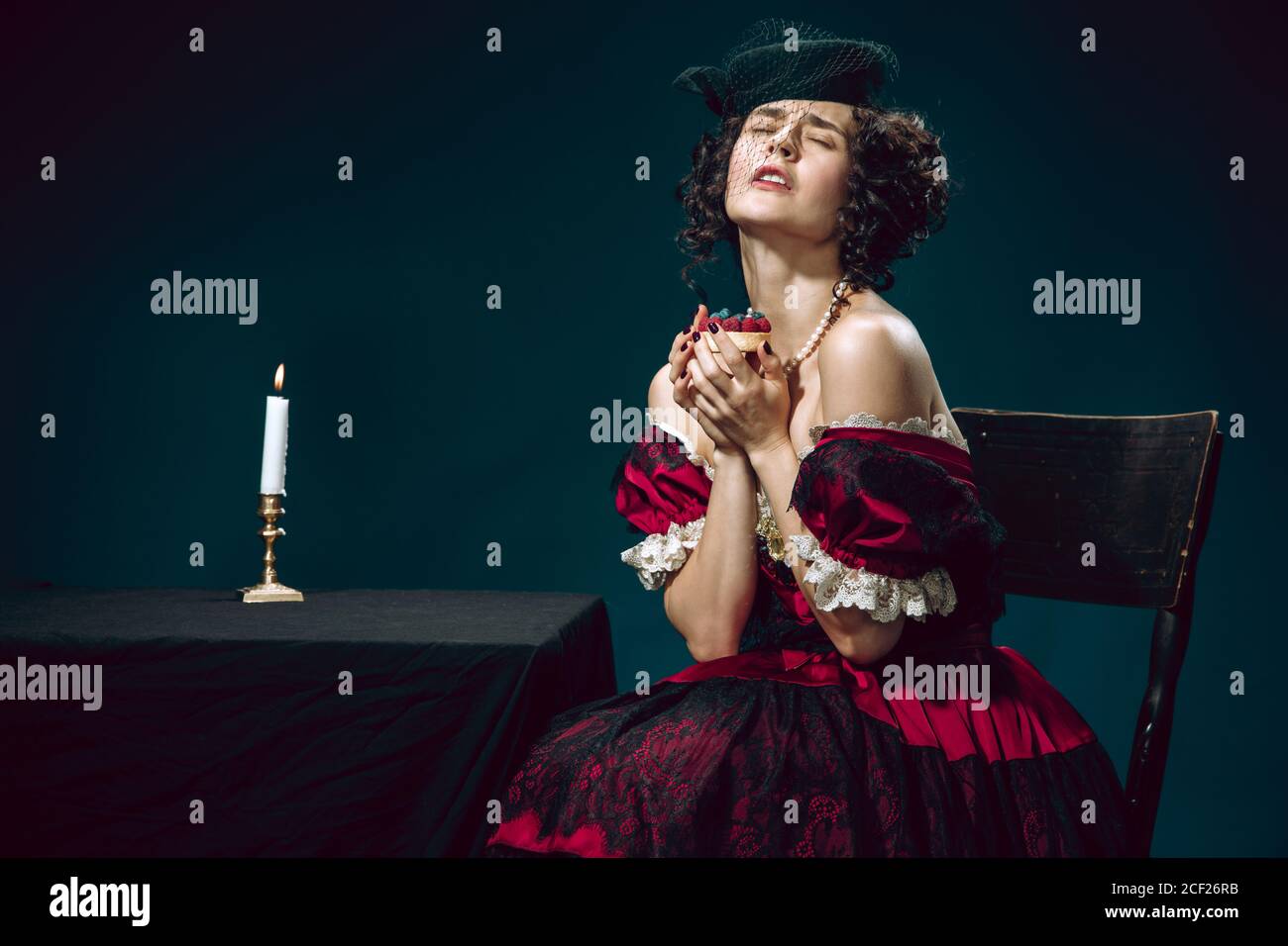 Passioned sweets. Young woman as Anna Karenina isolated on dark blue ...