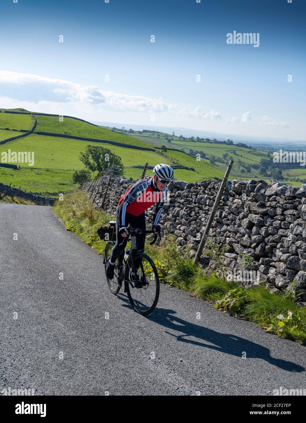 Male cyclist climbing out of Malham village in the Yorkshire Dales ...