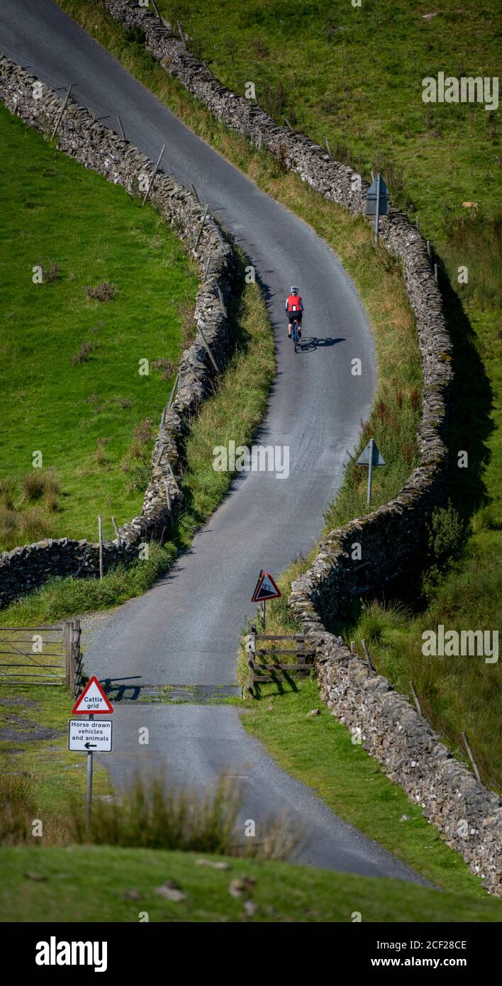 Female cyclist climbing a steep hill on her electric bike in the ...