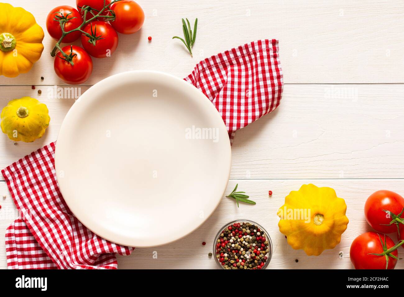 White wooden background with empty plate and ingredients, tomatoes and ...