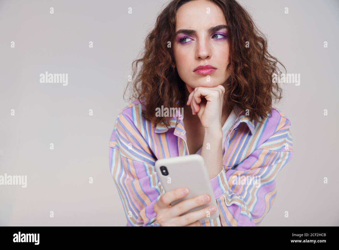 Image of ginger brooding woman thinking and using smartphone isolated ...