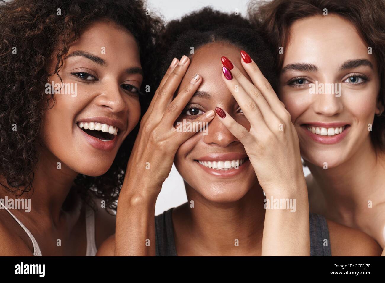 Portrait of three attractive multiracial women standing together and ...