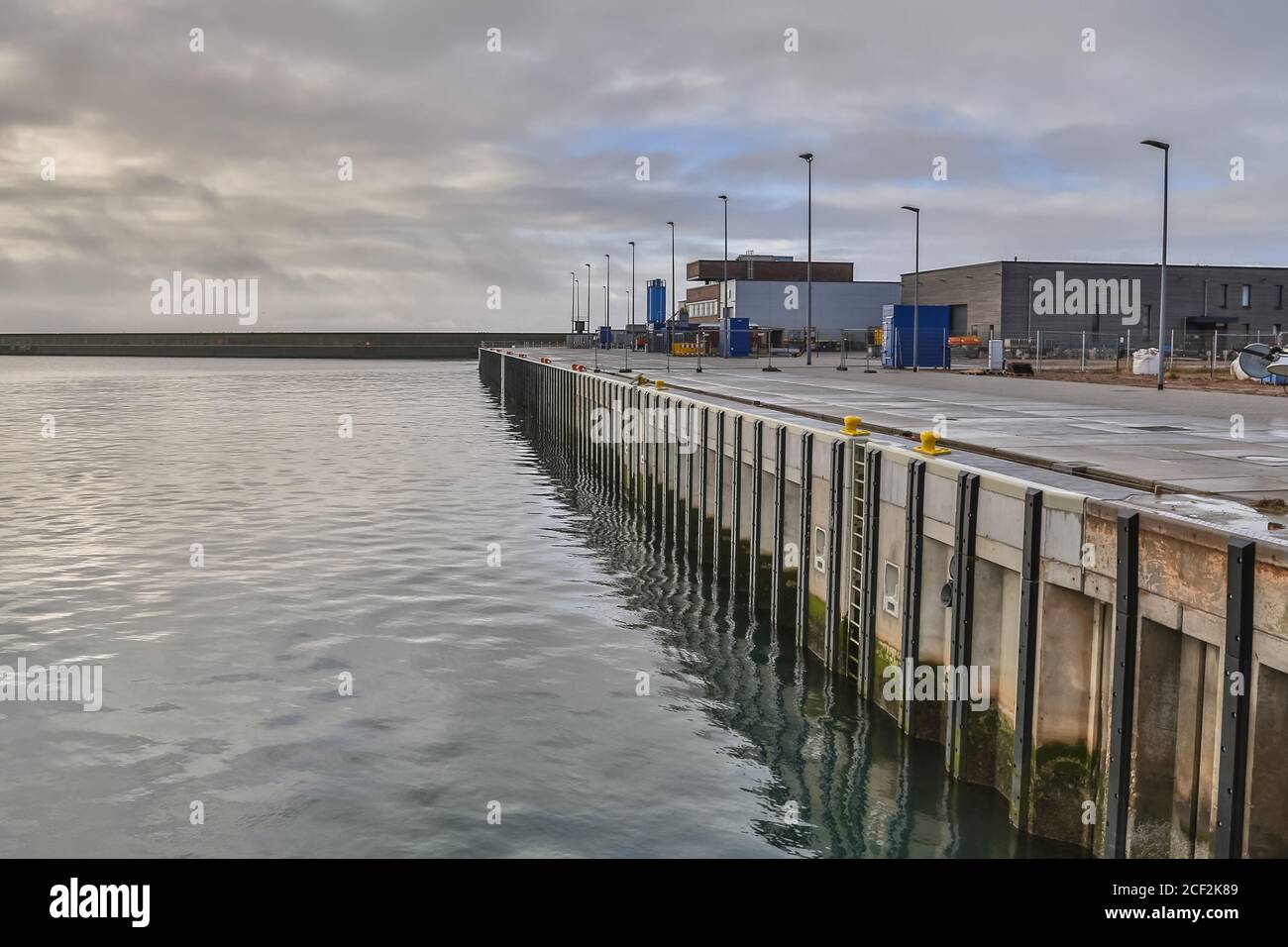Modern new concrete quay in maritime harbor with warehouses and water ...