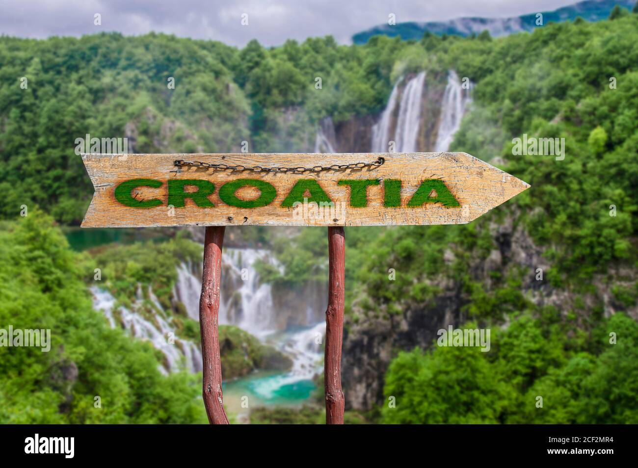 Wooden arrow road sign with word Croatia against waterfall and forest ...