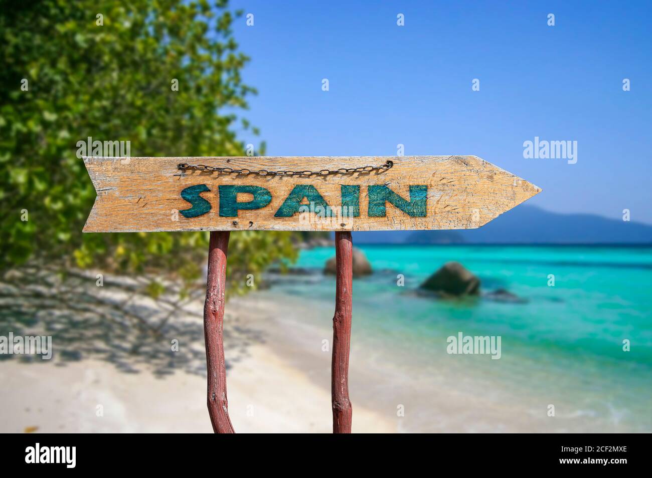 Wooden arrow road sign with word Spain against beach background. Travel ...