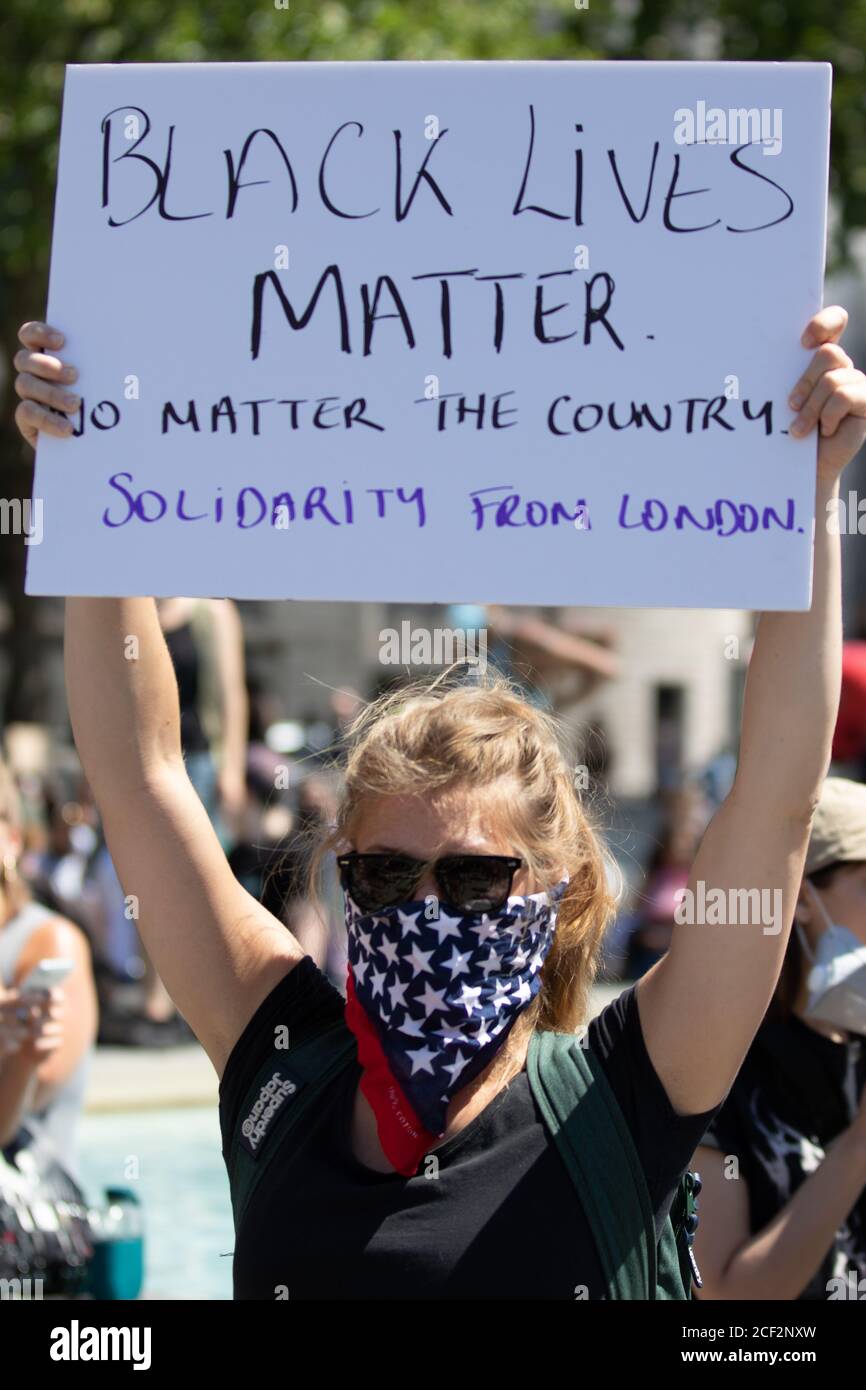 A female caucasian protester with an American Flag Bandana holds a ...