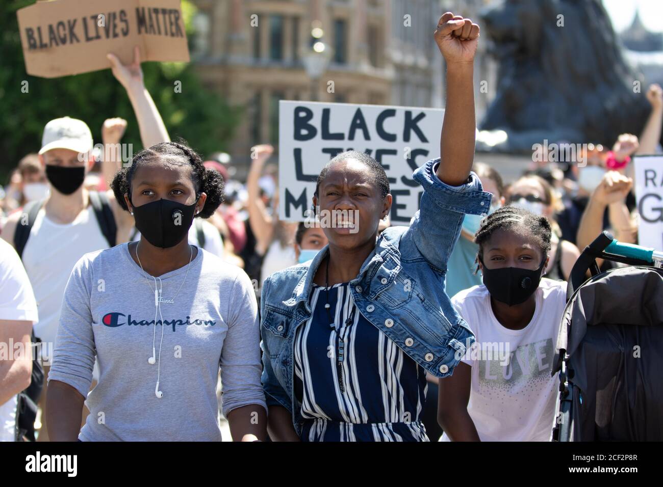 A black mother holds a raised fist next to her daughter during a Black ...