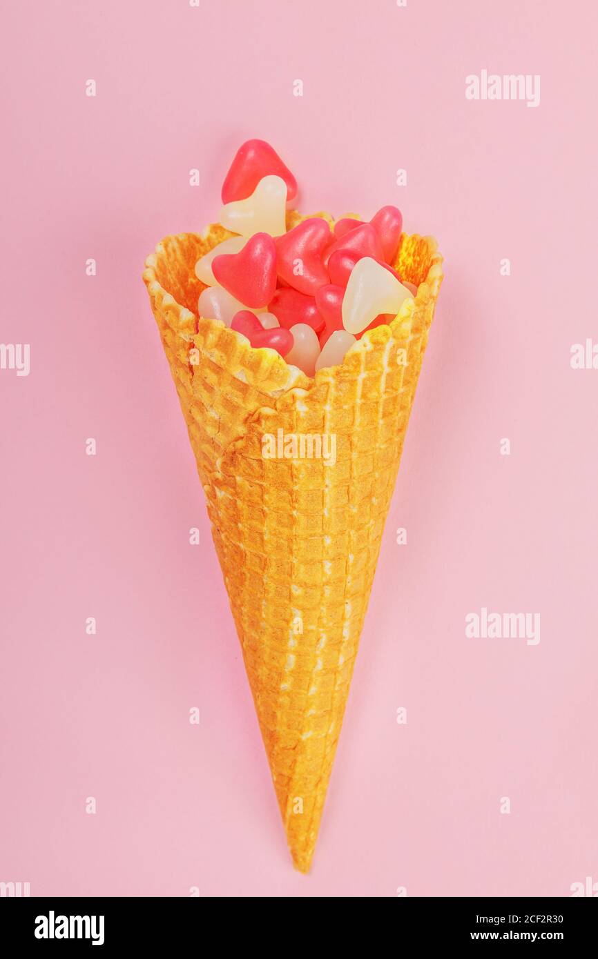 waffle cone with gummy hearts on a pink background. vertical frame ...