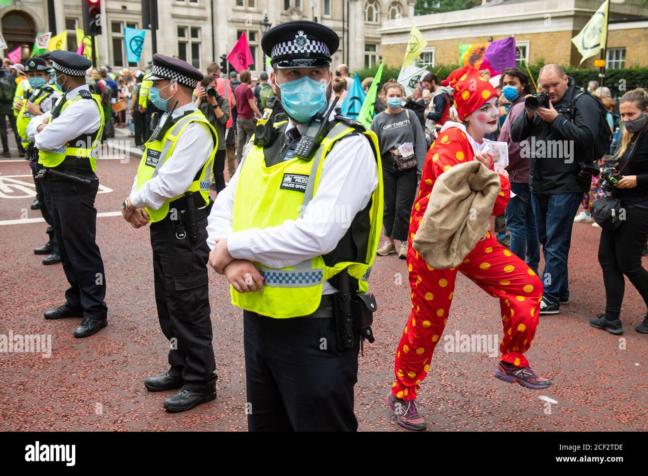 A protestor dressed as a clown dances amongst police officers outside ...