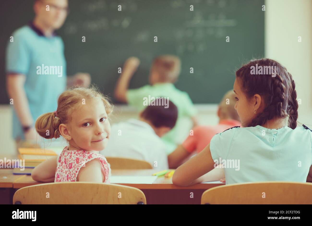 Young male teacher explaining math at the blackboard during a lesson at ...