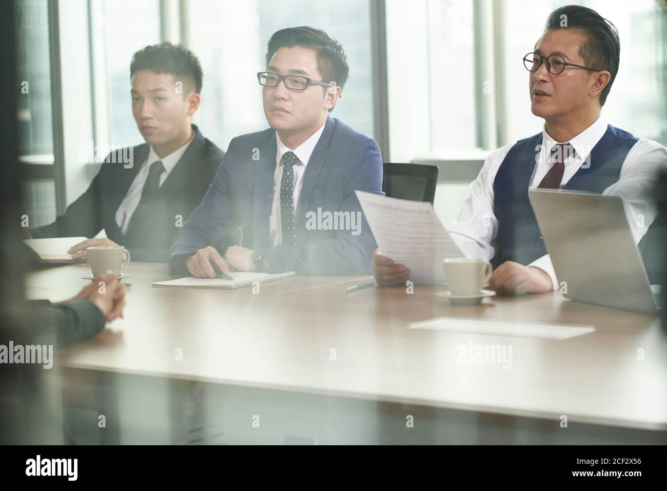 through-the-glass shot of a team of HR executives conducting an ...