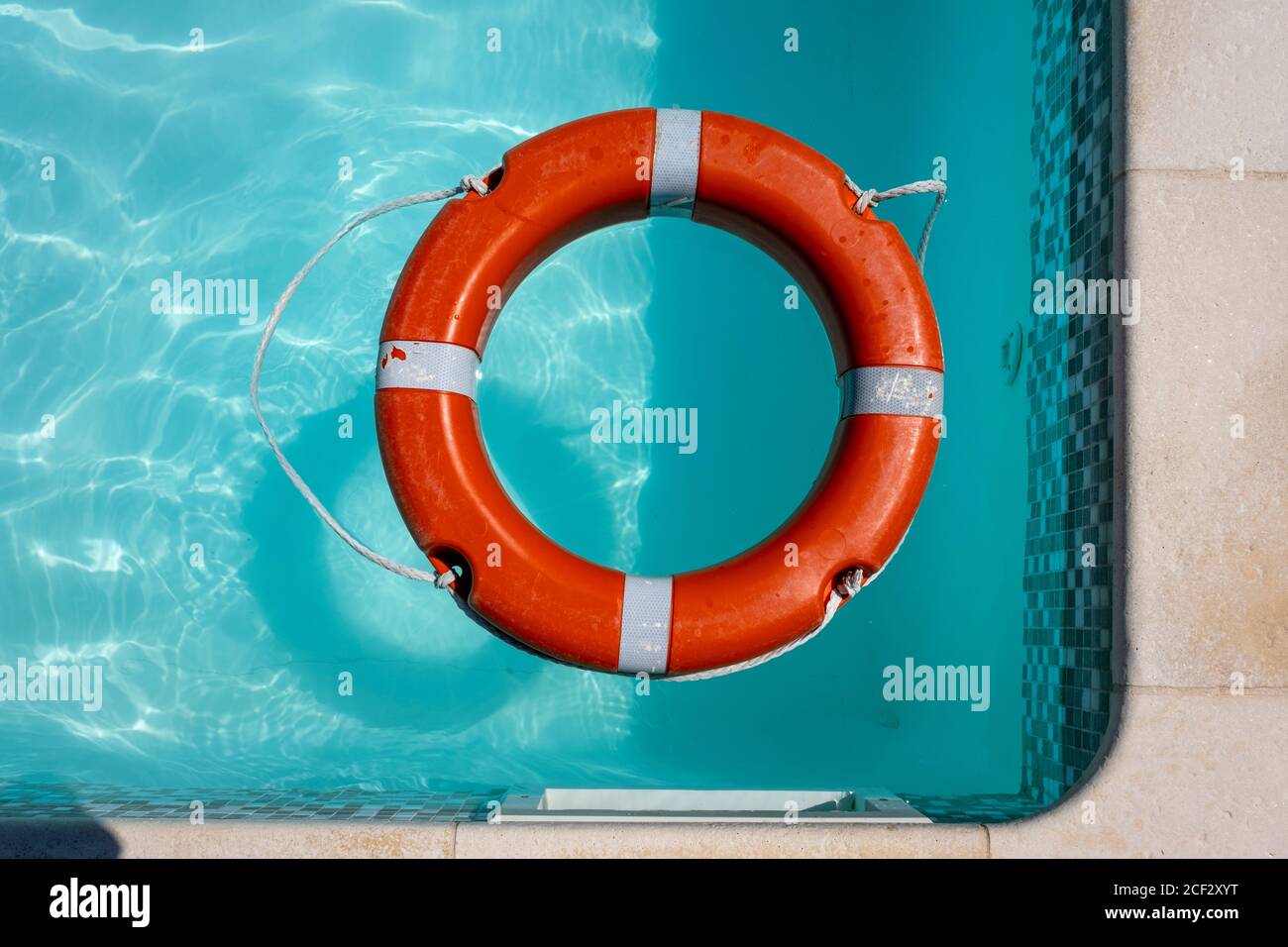 Orange lifebuoy floating on the surface of blue water in a pool Stock ...