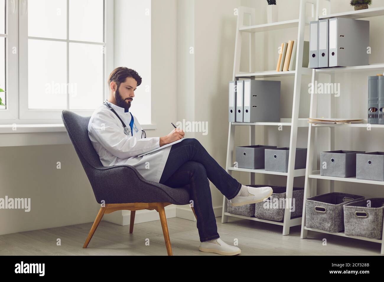 Serious male doctor filling patient card at his medical office. General ...