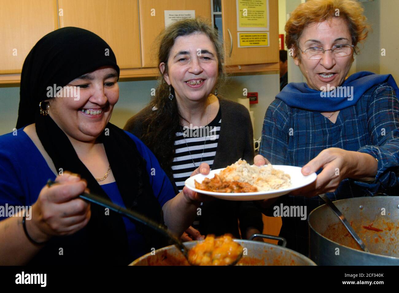 Volunteers serve curry to refugees and asylum seekers in a soup kitchen ...
